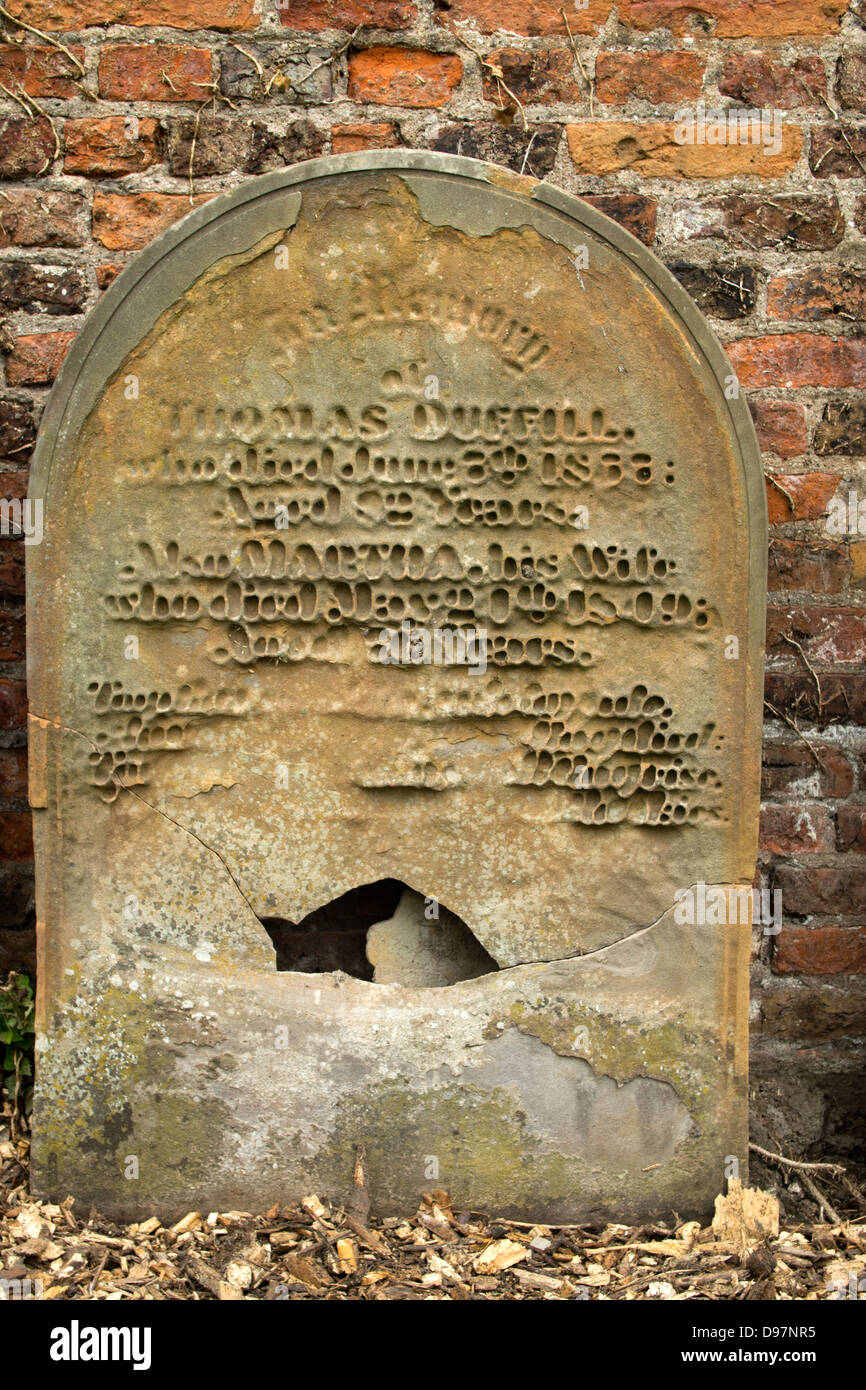 Weather Eroded Gravestone, against a brick wall Stock Photo - Alamy