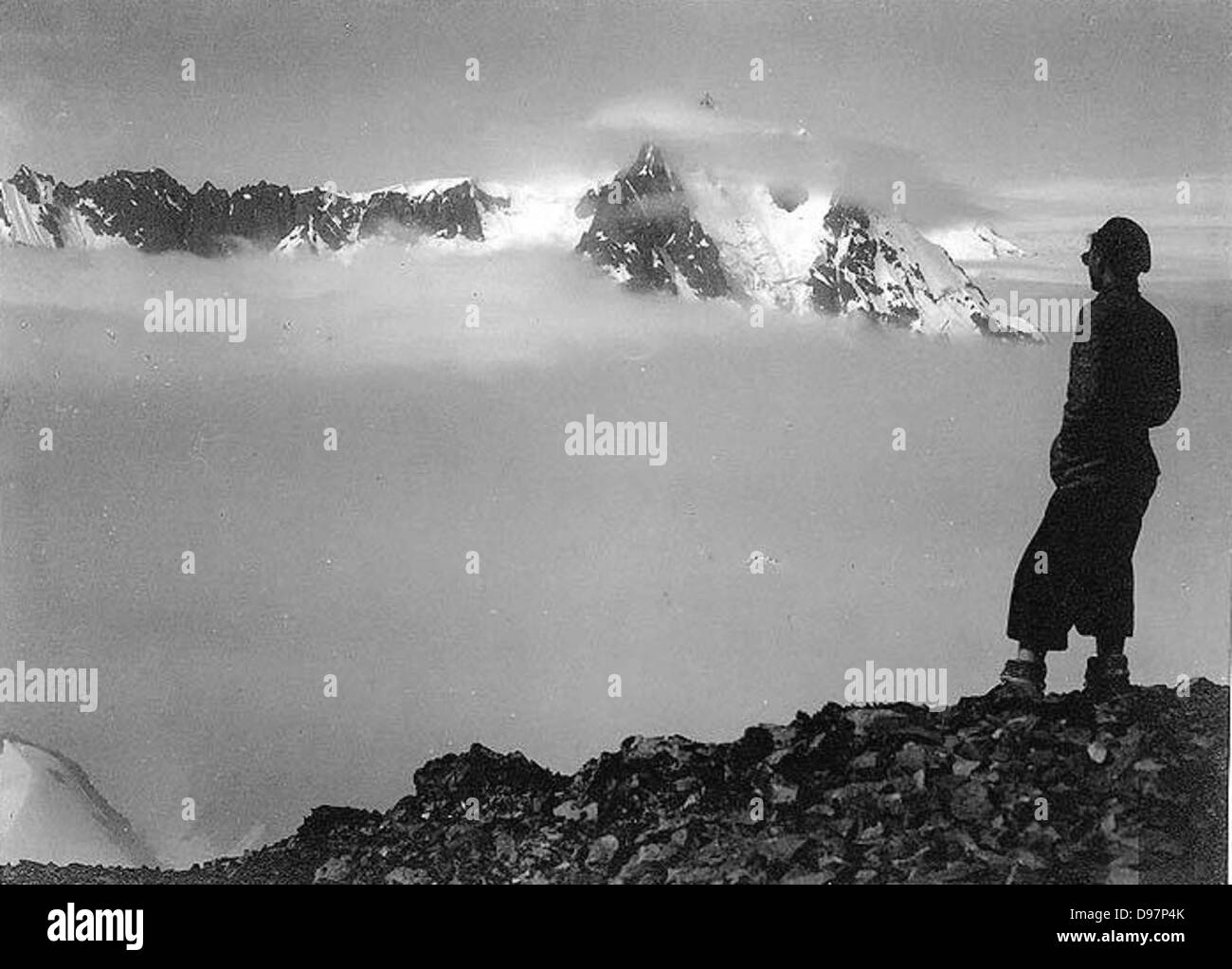 A hiker views Mount Shuksan from Mount Ruth, surrounded by clouds and ...