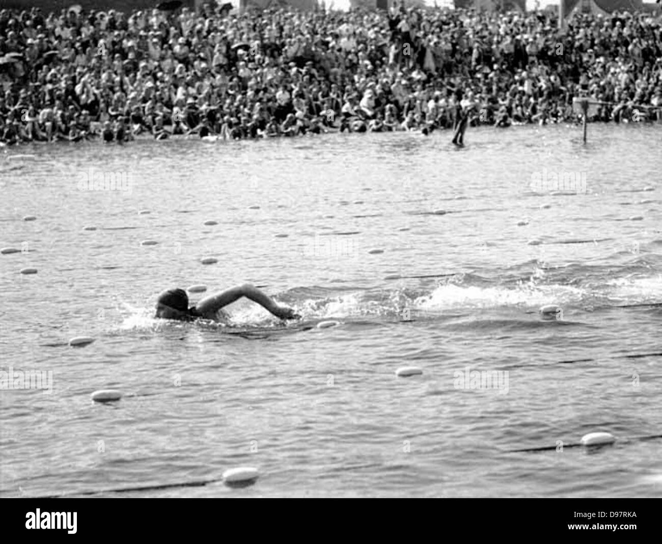 Swimmer Helene Madison swimming in a lake while a crowd watches in the ...