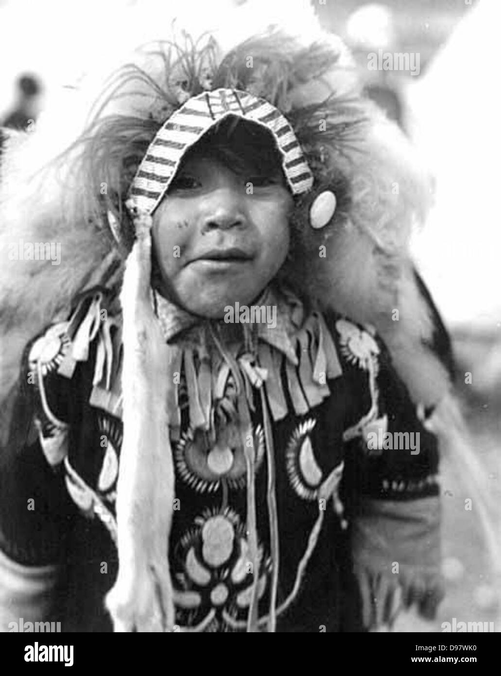 This photograph shows a young Native American boy dressed in ...
