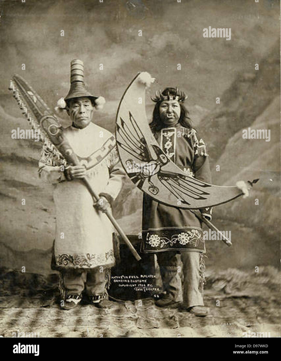 This studio portrait shows a Tlingit man and woman in full ceremonial ...