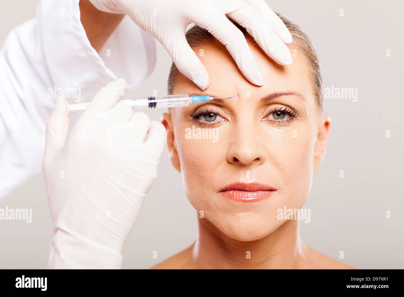 cosmetic surgeon giving face lifting injection to mature woman Stock ...