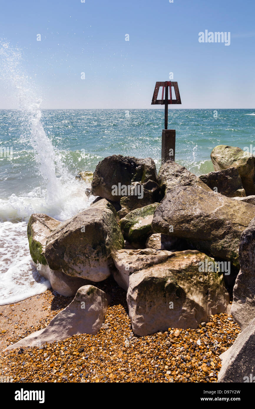 Waves splashing / crashing on breakwater stone groyne on beach at ...