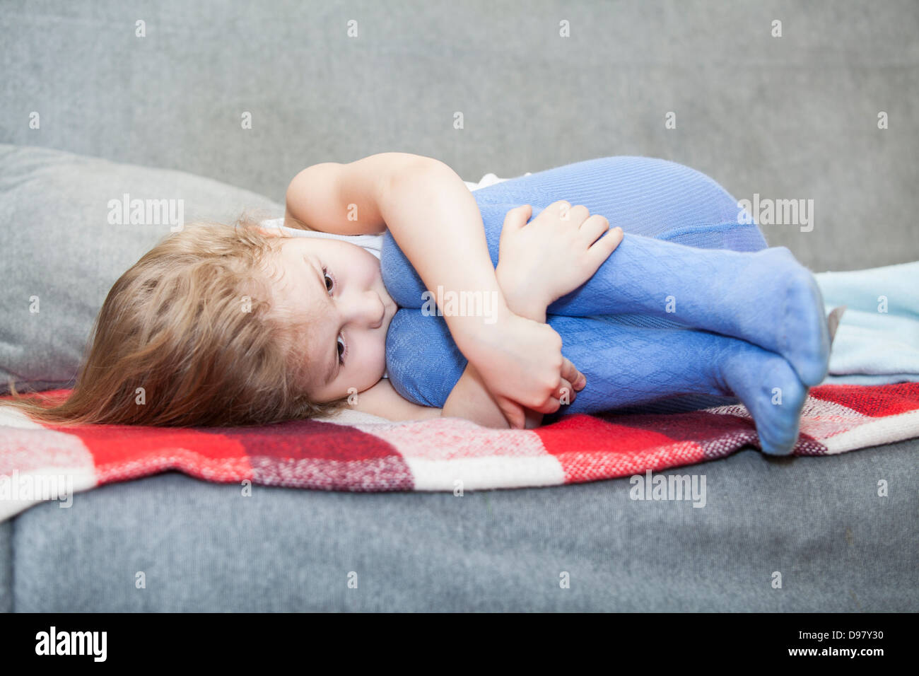 Small Caucasian defenseless child huddled on the couch Stock Photo - Alamy