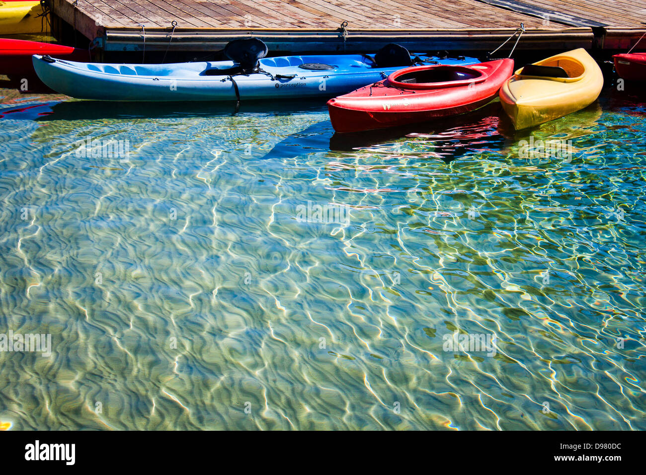 Colorful kayaks tied to edge of boat dock at Redfish Lake, surrounded ...