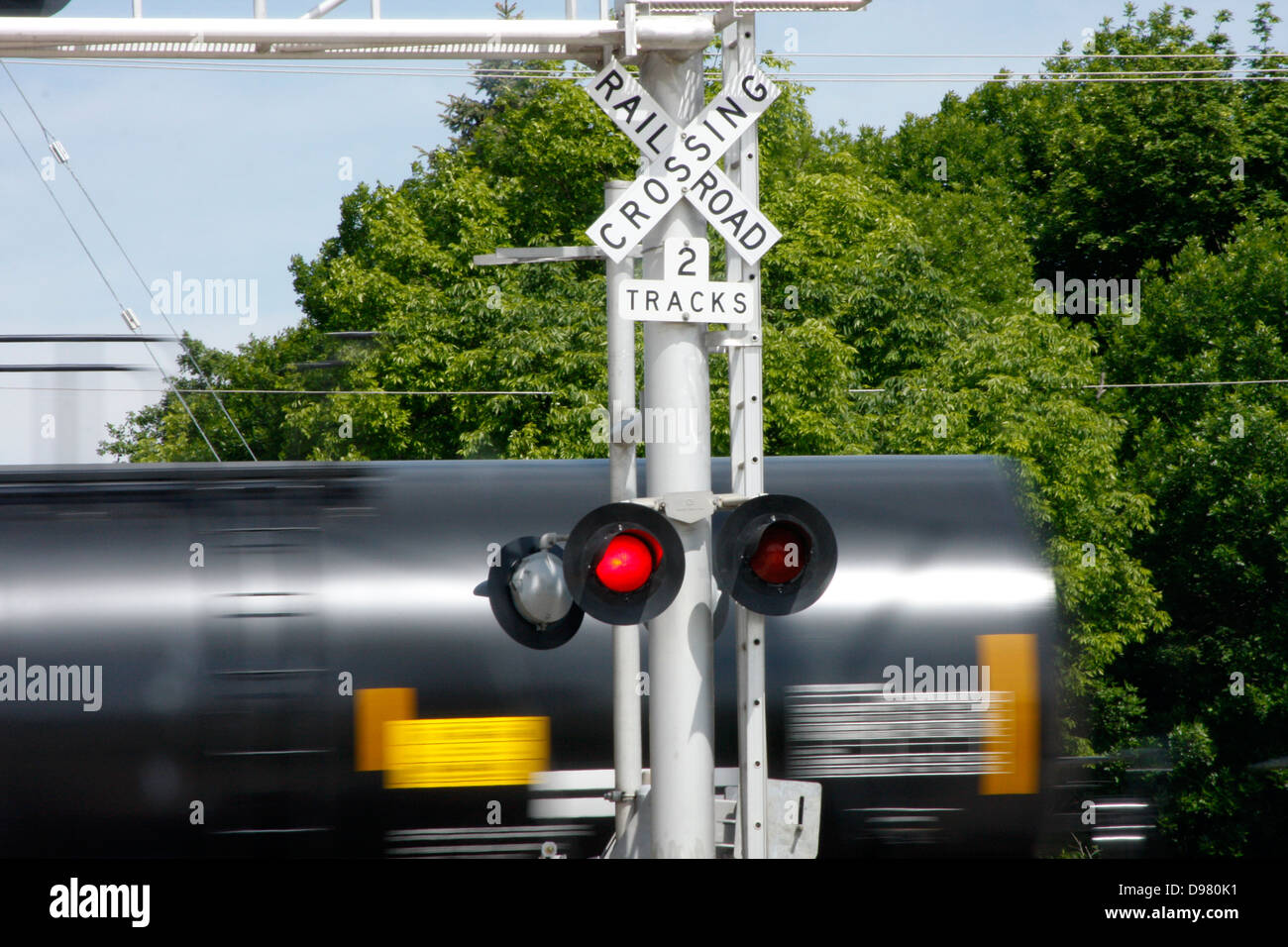 Railroad crossing with a tanker train passing by quickly Stock Photo ...