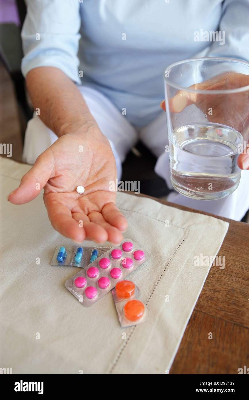 Woman taking her medication with a glass of water Stock Photo - Alamy