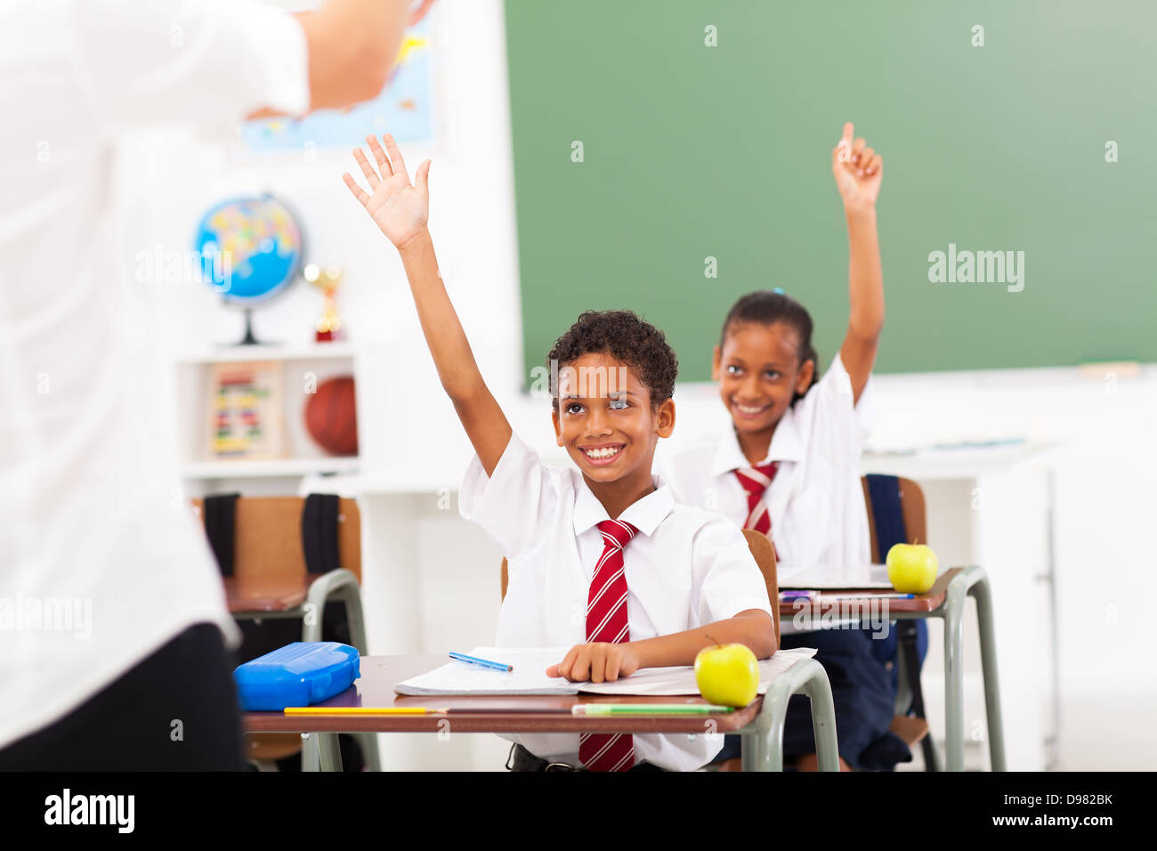 elementary school students arms up in classroom Stock Photo - Alamy