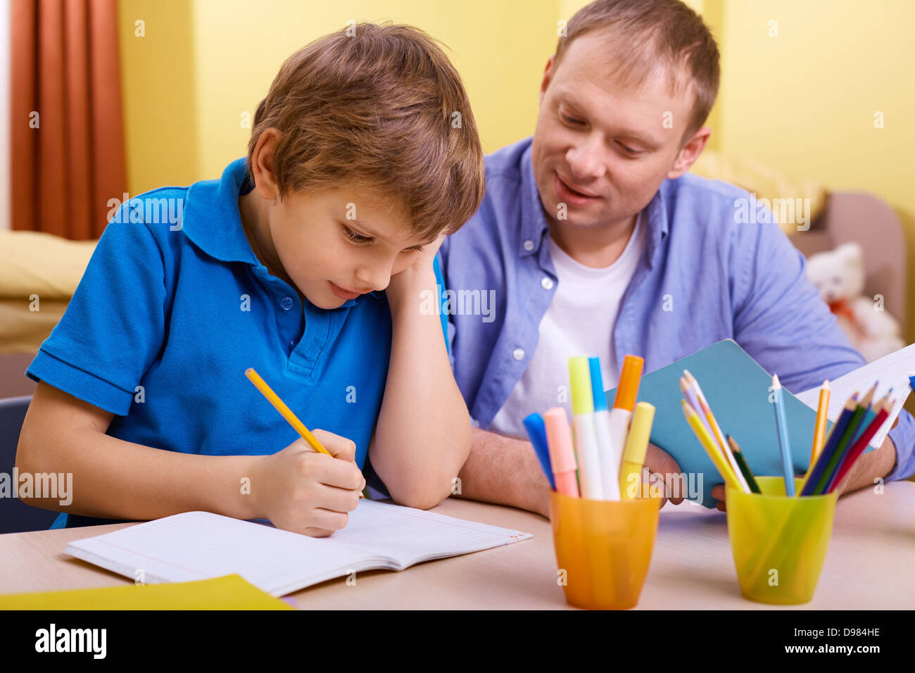 Portrait of cute schoolboy and his father making schoolwork at home ...