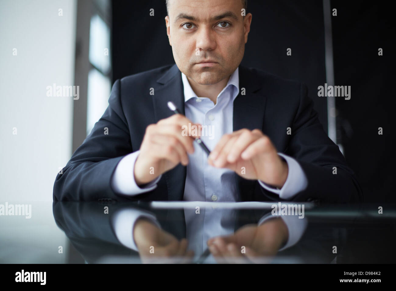 Serious businessman looking at camera at workplace Stock Photo - Alamy
