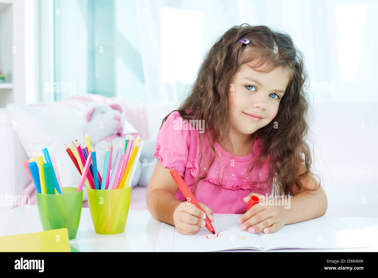 Portrait of lovely girl looking at camera while drawing with colorful ...