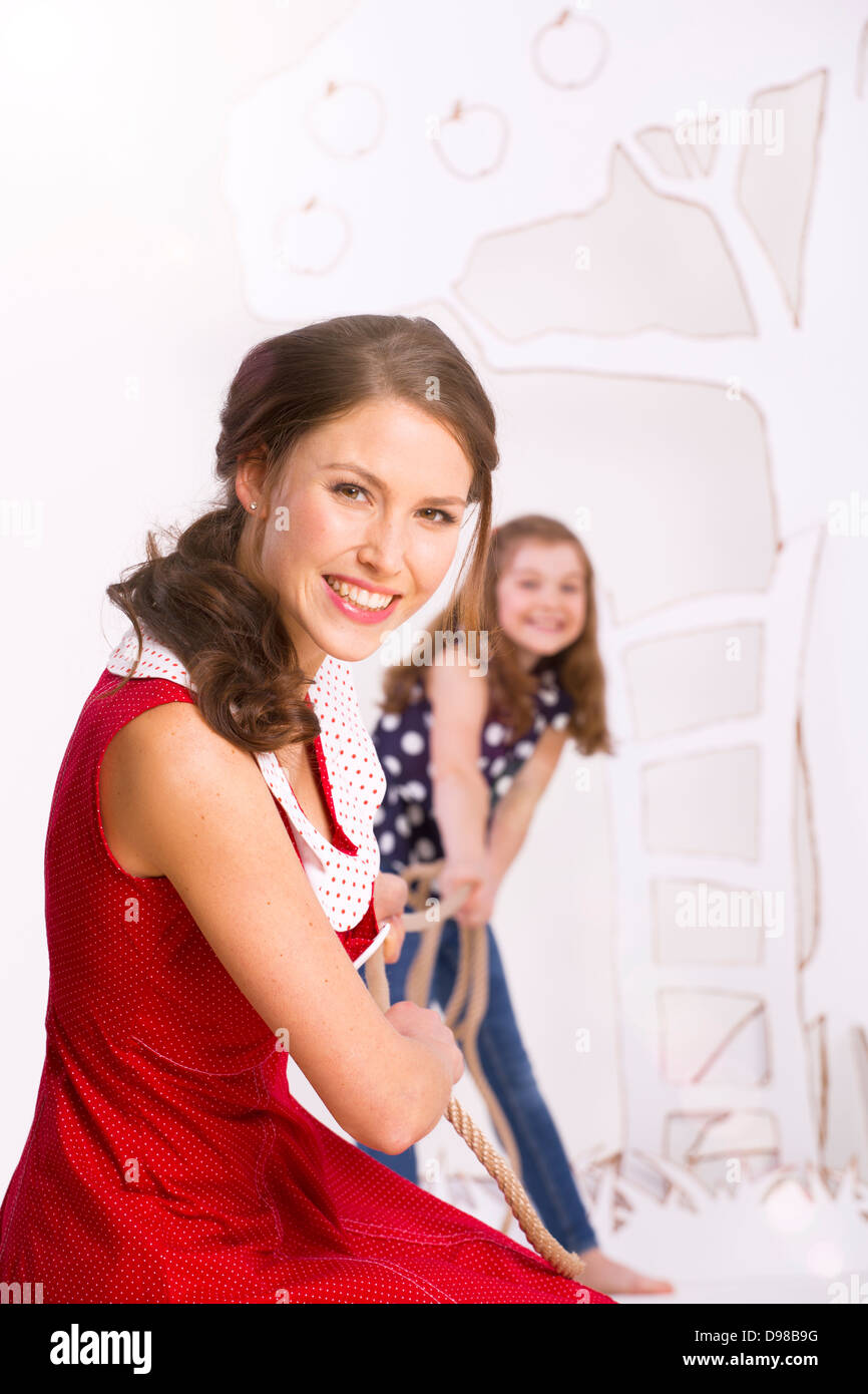 Portrait of mother and daughter pulling rope, smiling Stock Photo - Alamy