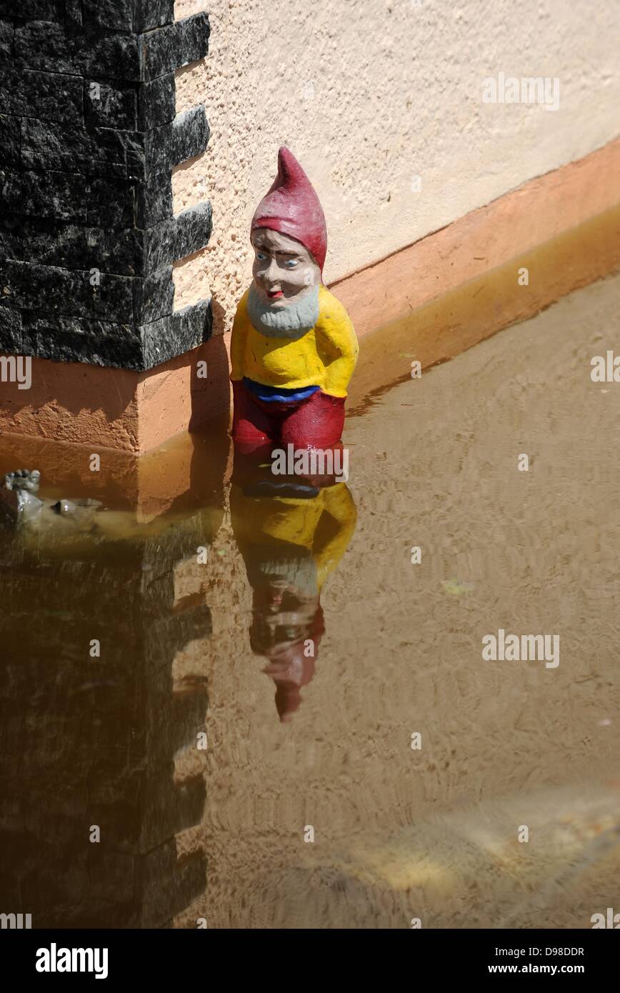 A figurine of a dwarf stands next to a house in a flooded area of ...