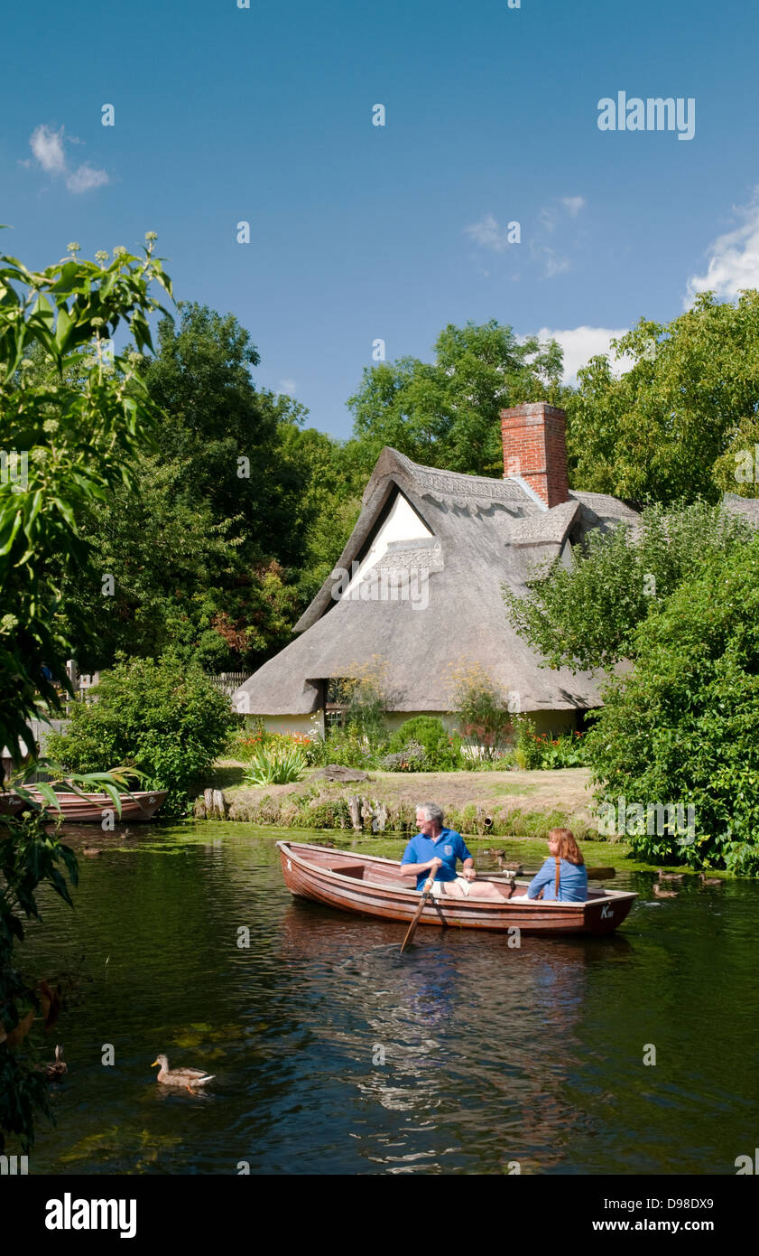 A couple seen boating on the River Stour by a cottage at Dedham Stock ...