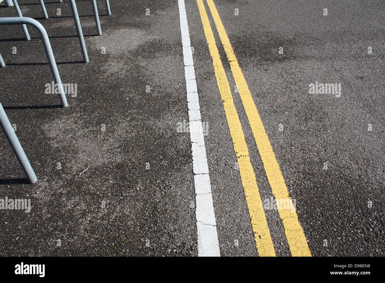 Detail of road showing white and double yellow lines and bike rack ...