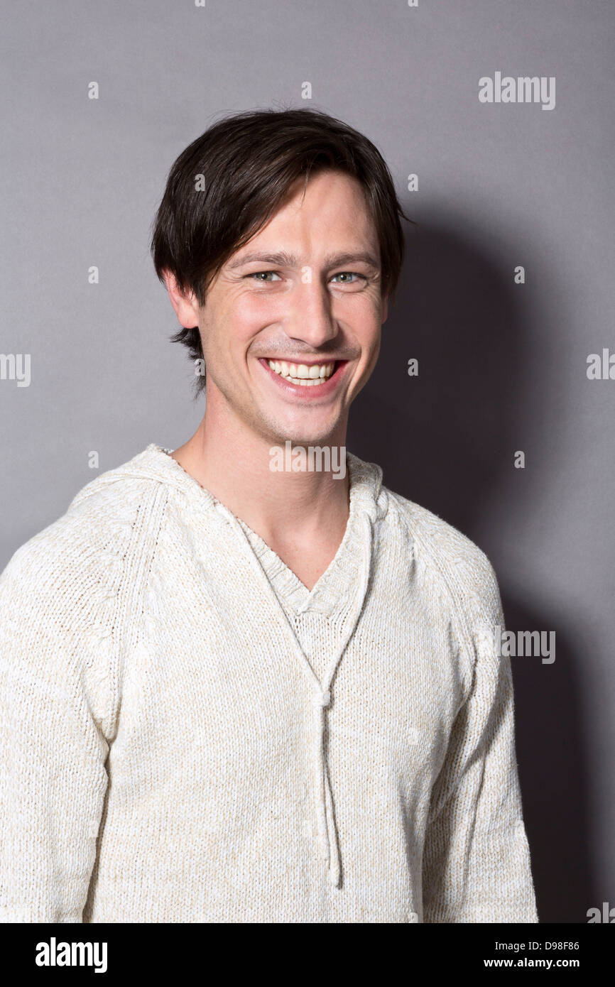Portrait of young man against grey background, smiling Stock Photo - Alamy