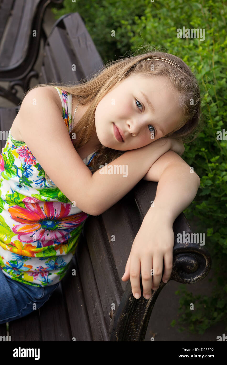 beautiful young girl is sitting on the bench at park in summer Stock ...