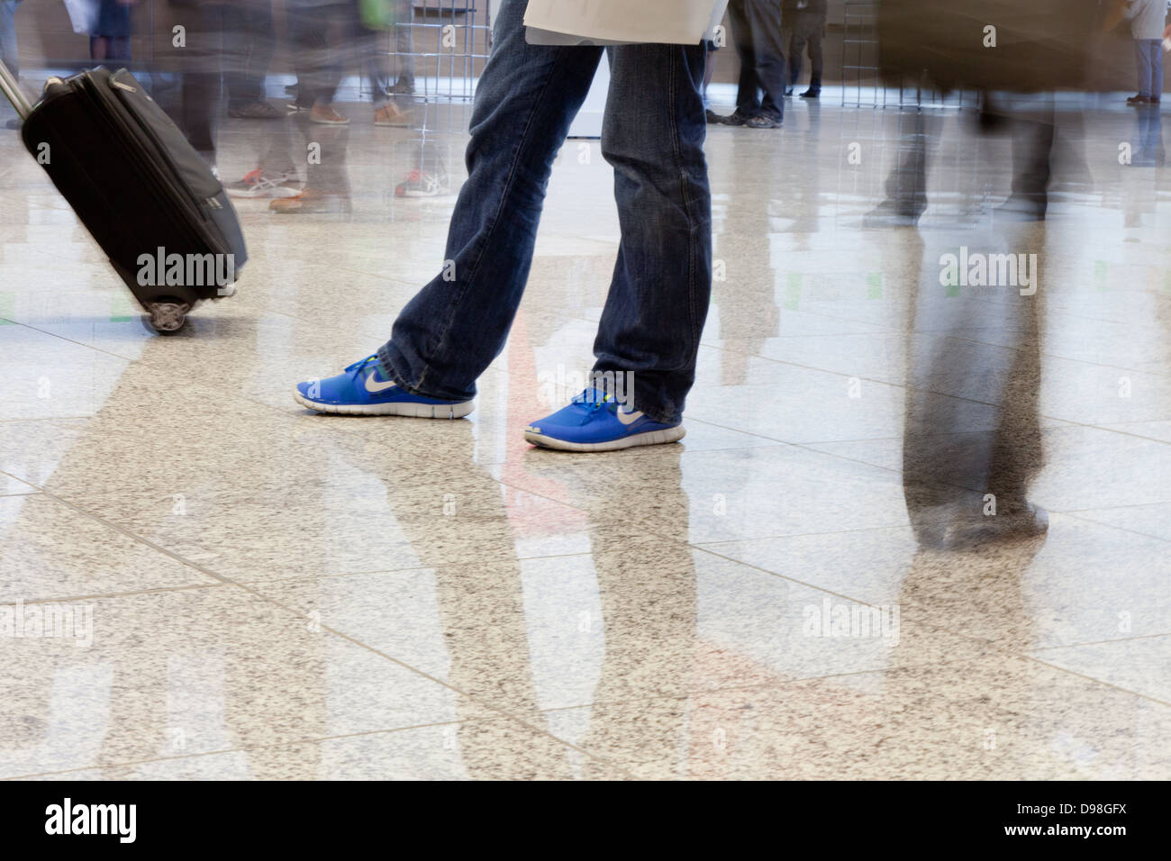 Trainer clad feet standing still on a reflective floor with movement ...