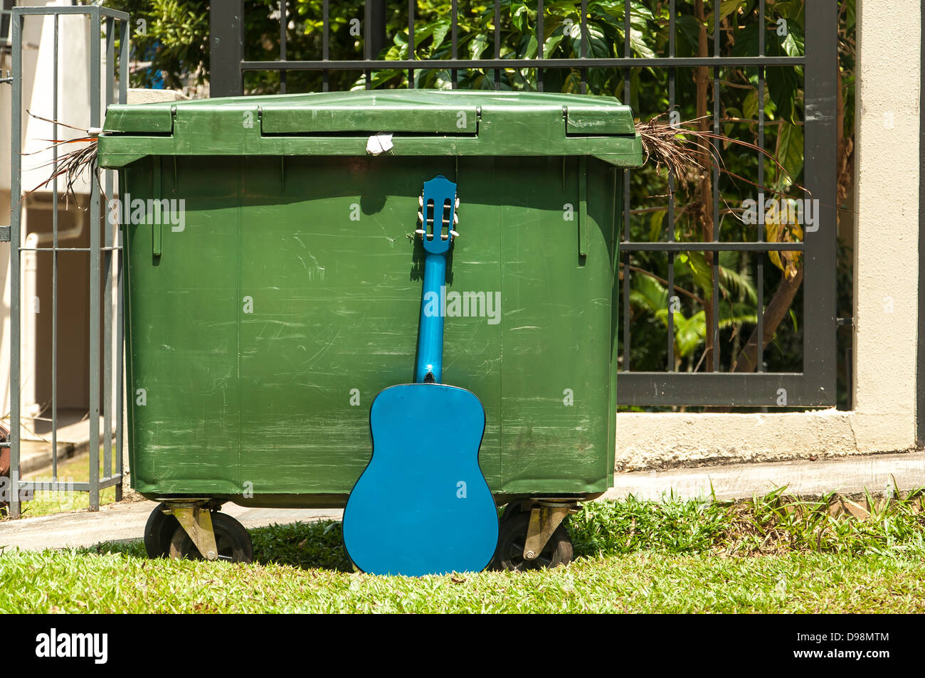 Blue guitar thrown out in green dustbin garbage bin Stock Photo - Alamy