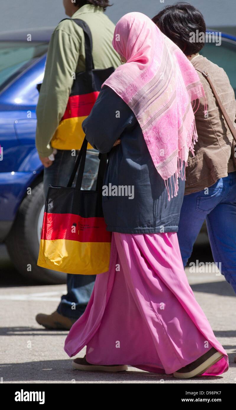A woman with a headscarf carries a bag with the German national colours ...