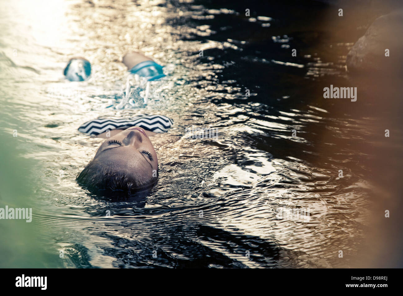 Woman floating in water during sunset Stock Photo - Alamy