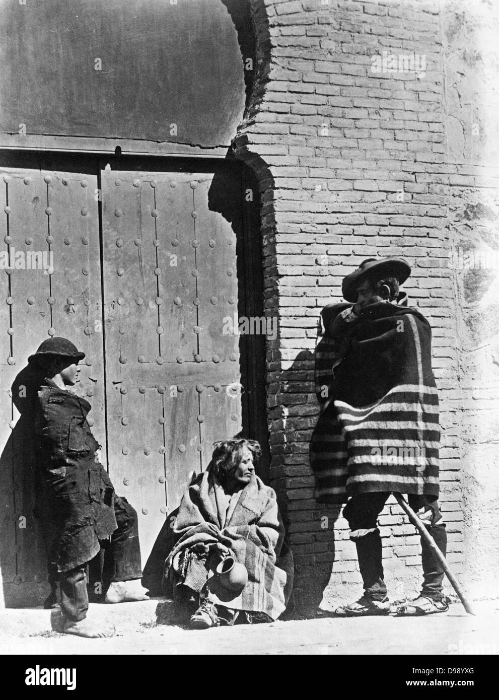 Three beggars, a man, woman, and child in front of convent doors ...