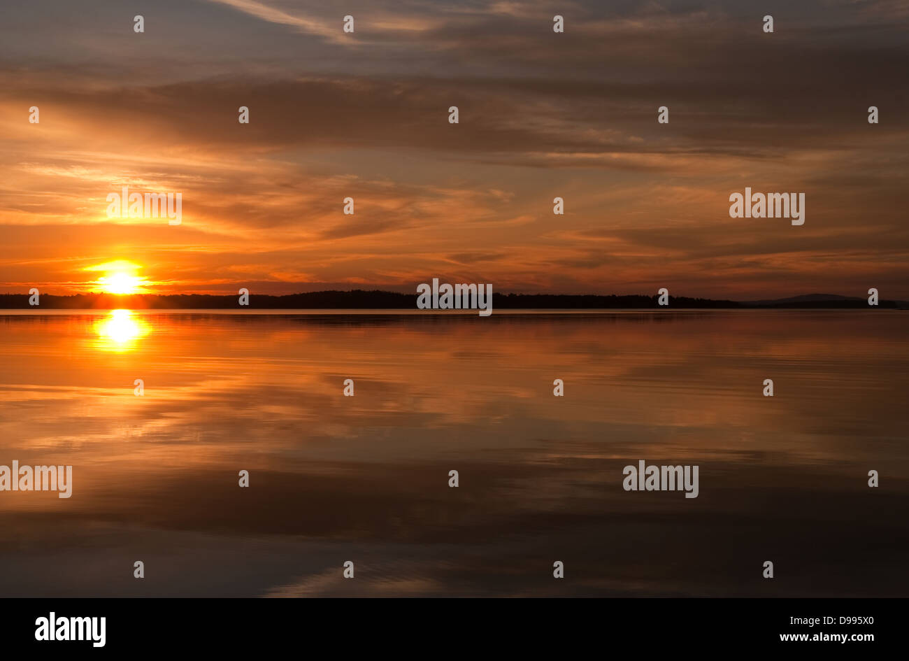 Dramatic sunrise over land reflected in water Stock Photo - Alamy