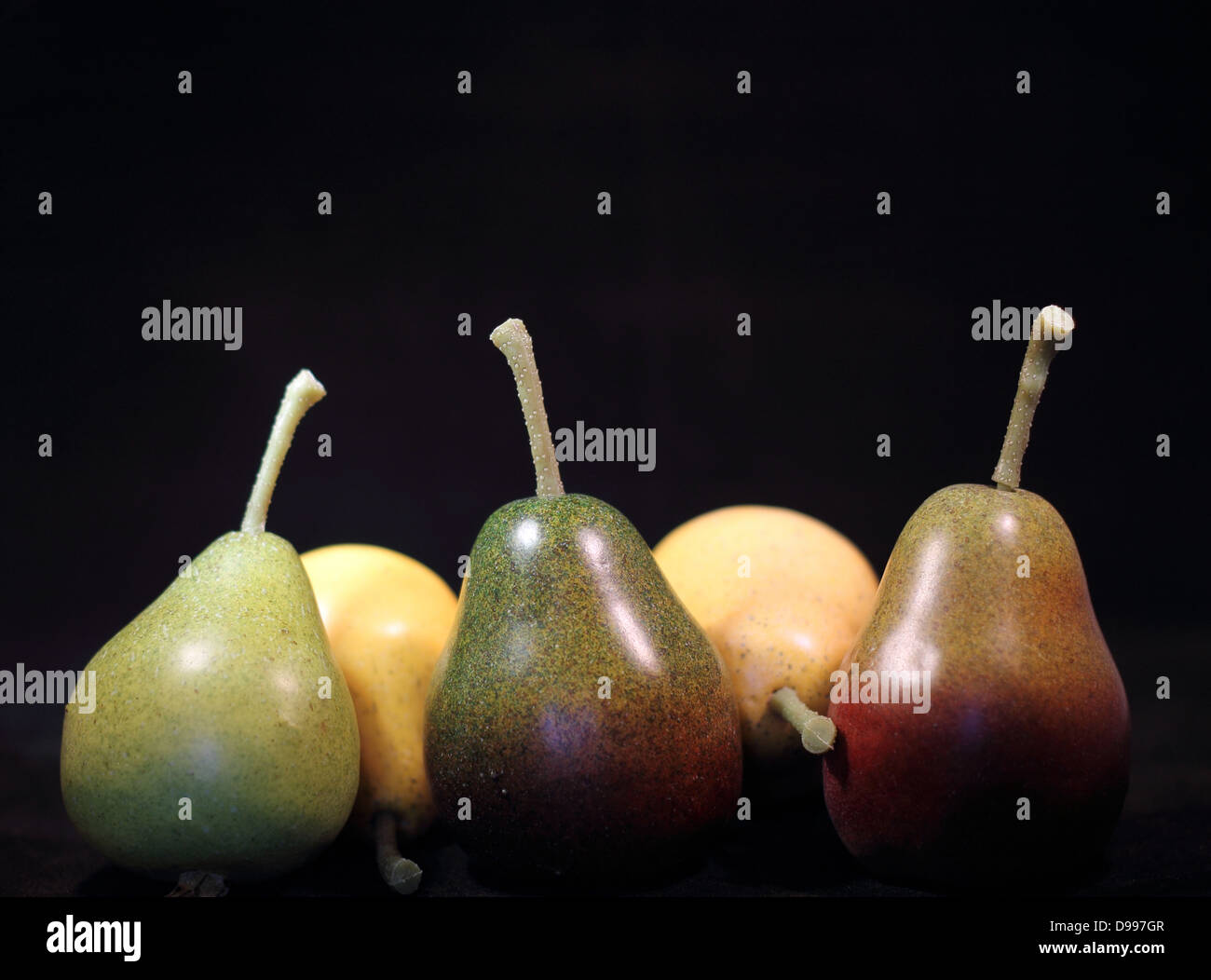 Five pears- two yellow and three green on a black background Stock ...