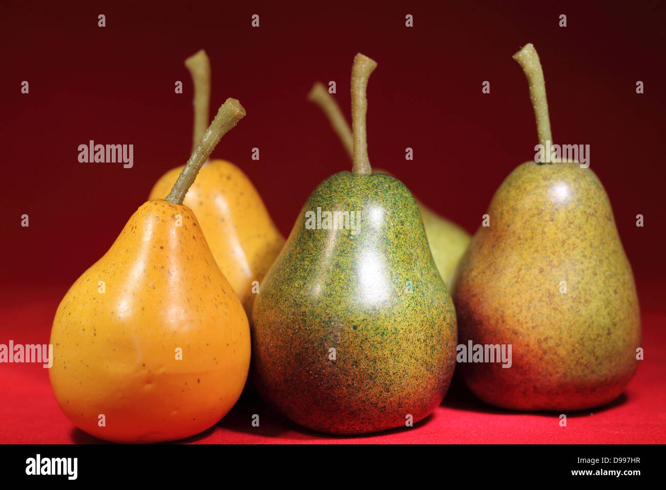 Five pears, two yellow and three green on red backdrop. Focus on three ...