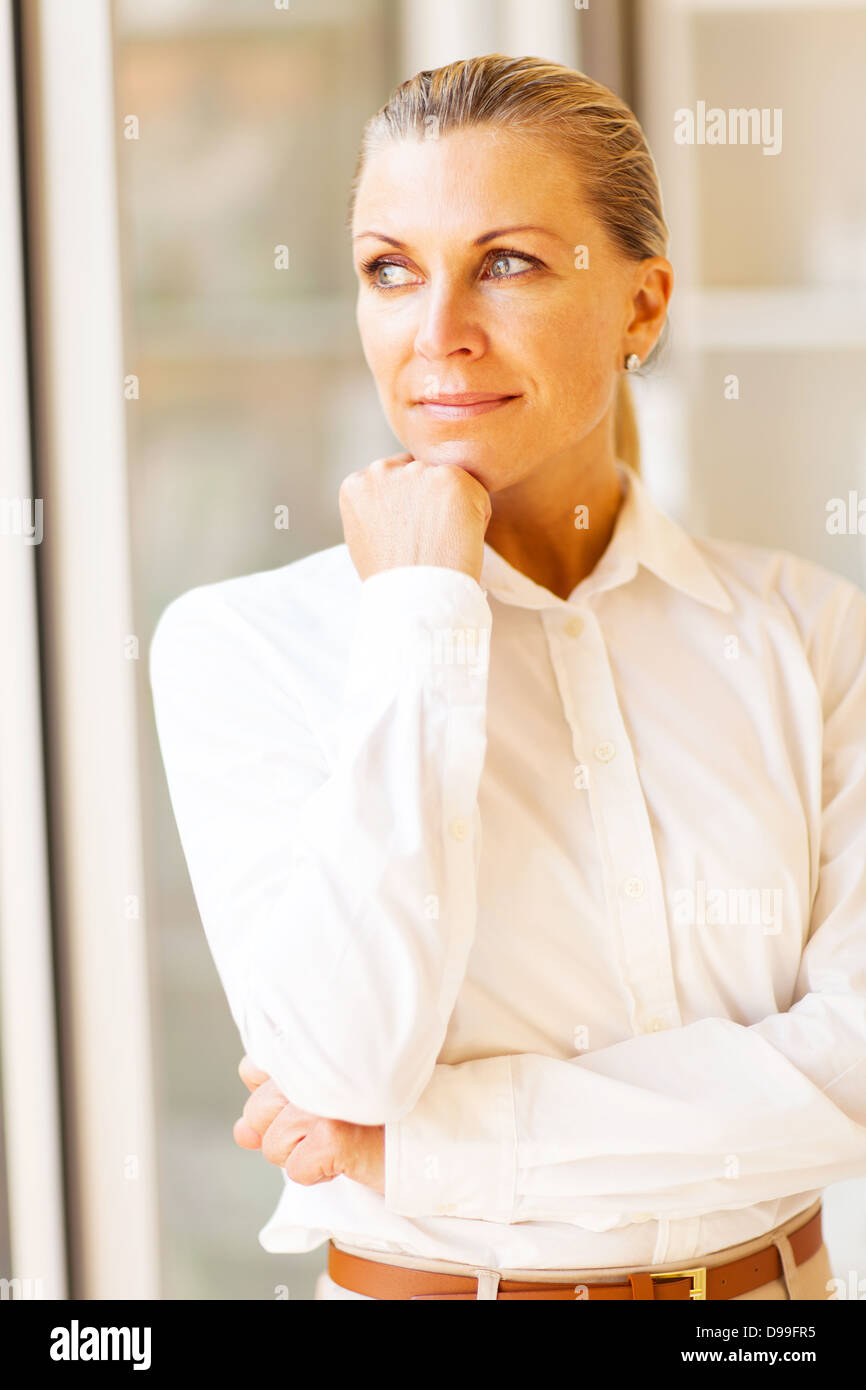 thoughtful female senior office worker looking outside window Stock ...