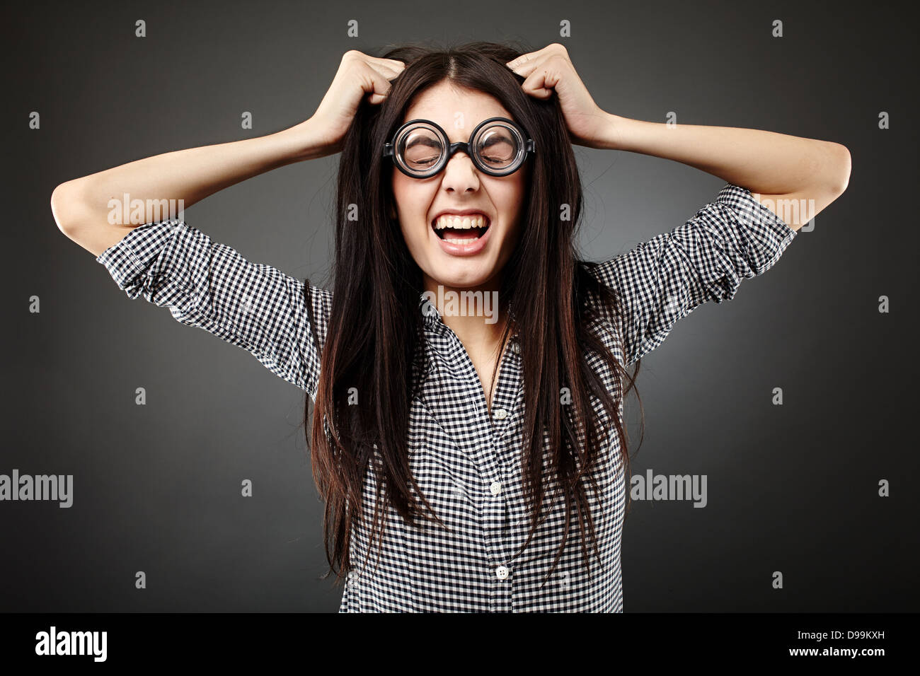 Closeup of teenage nerd shouting ang pulling her hair over gray ...