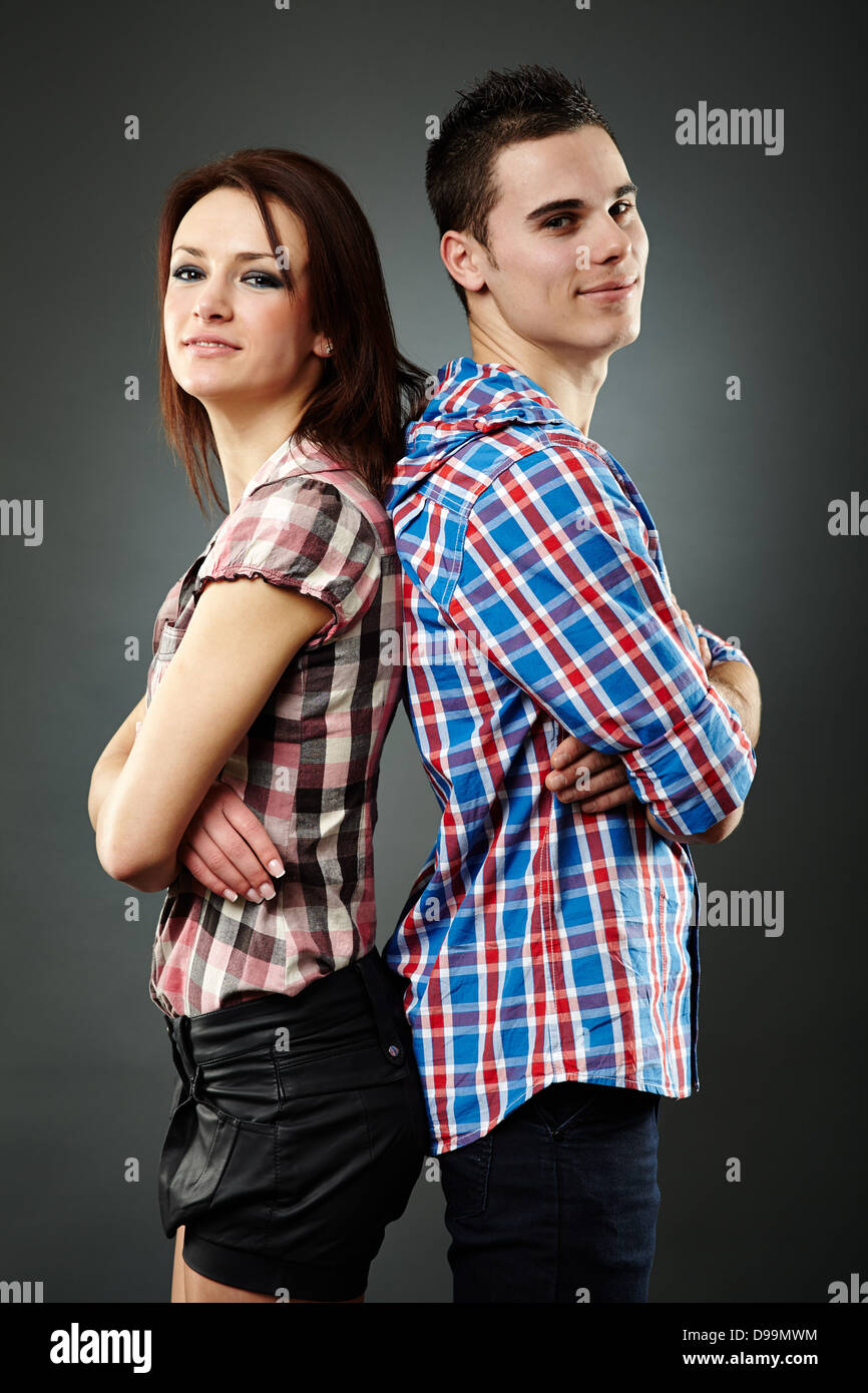 Closeup of young standing back to back, with their arms crossed ...