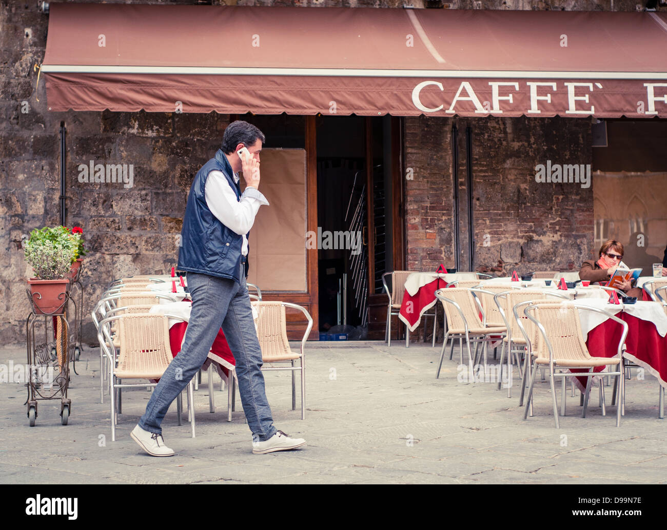 A man talking on his mobile walking past a Cafe in Siena, Italy Stock ...