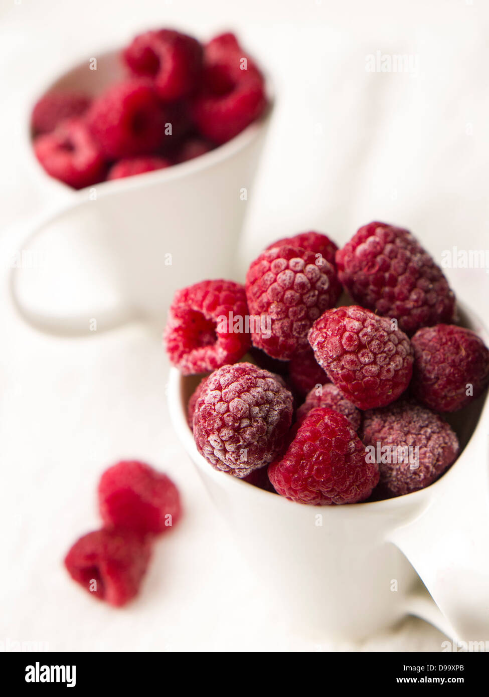 Frozen raspberries in white cups on a white table Stock Photo - Alamy
