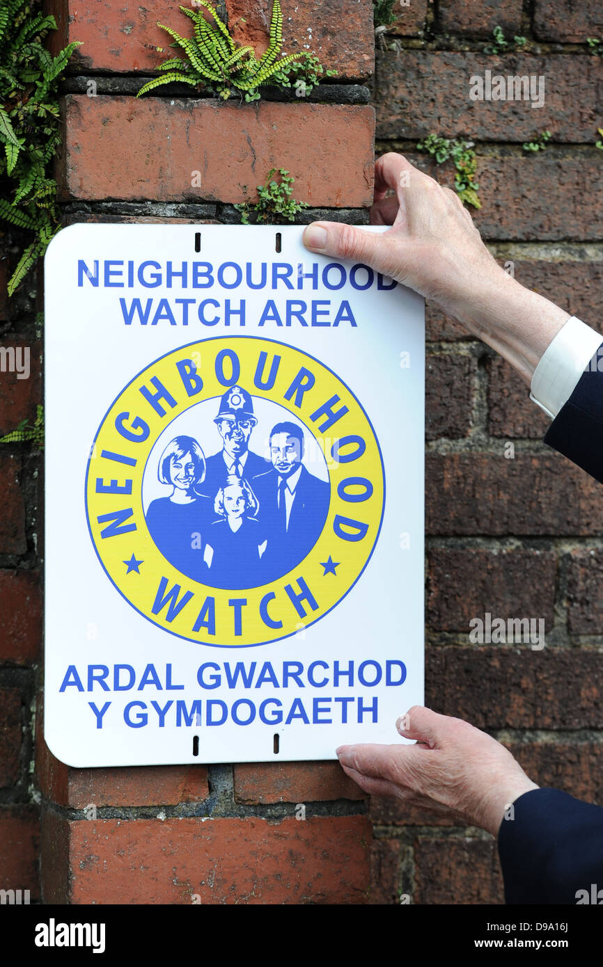 A man nailing a neighbourhood watch sign to a wall Stock Photo - Alamy