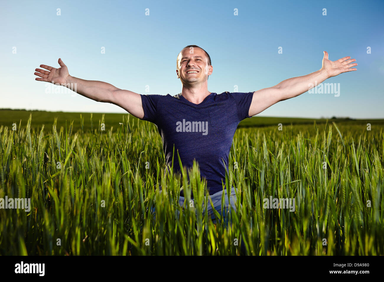 Farmer with his arms raised in a wheat field, happy about his crops ...