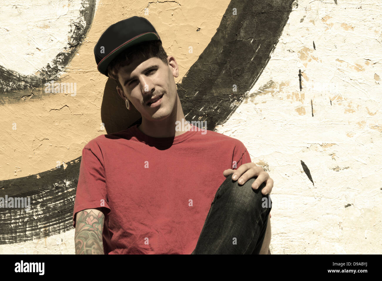 A young Rapper leaning against a wall Stock Photo - Alamy