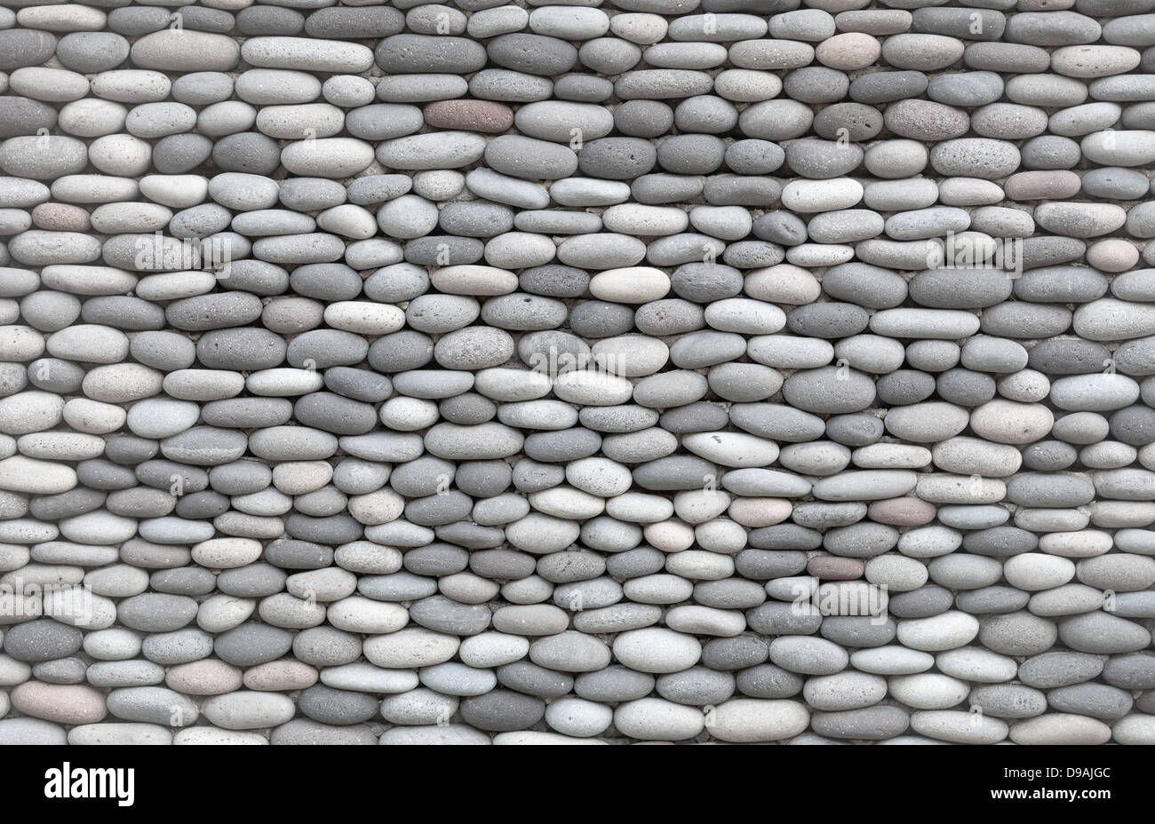 Background - a wall decorated with smooth round stones Stock Photo - Alamy