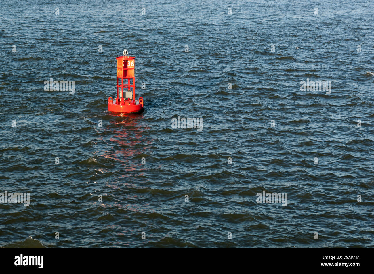 Bright red maritime buoy in the middle of the ocean, surrounded by blue ...