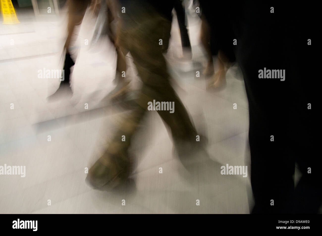 Blurred motion of pedestrian legs and feet walking on sidewalk at night ...