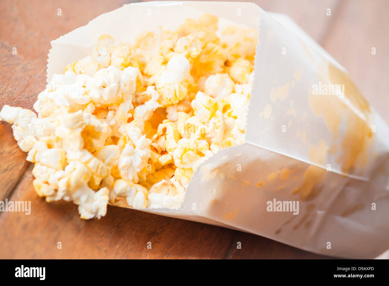 Popcorn packet opened with corn spilling out Stock Photo - Alamy