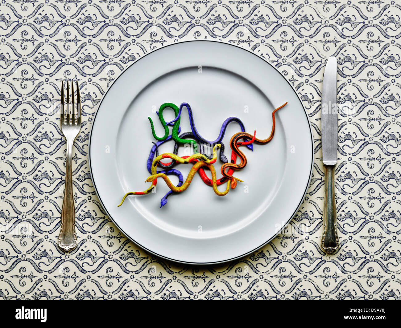 Toy snakes on plate with fork and knife, close up Stock Photo - Alamy