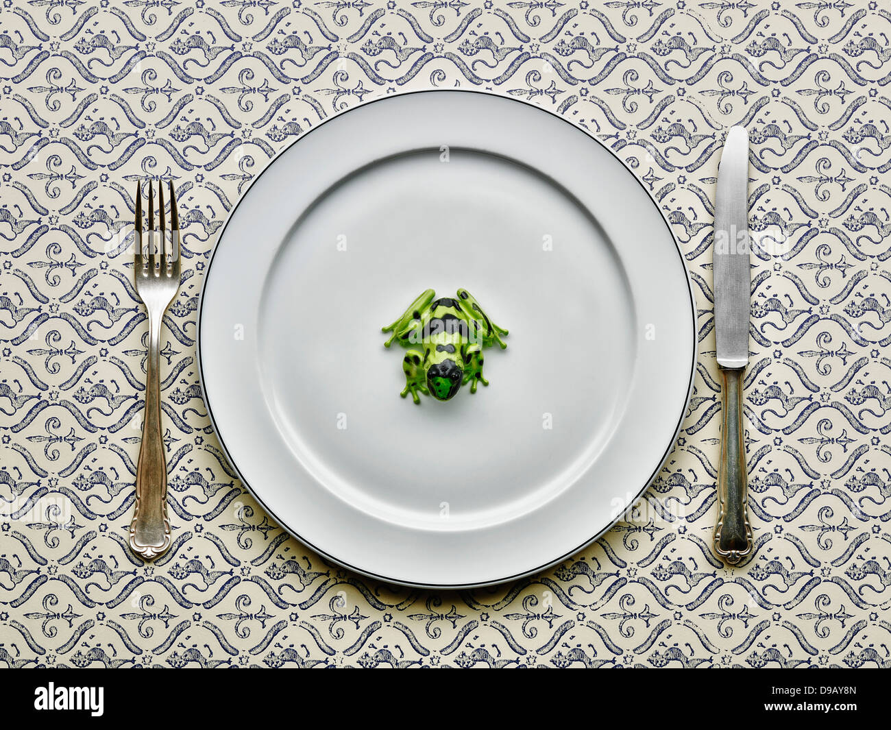 Toy frog on plate with fork and knife, close up Stock Photo - Alamy