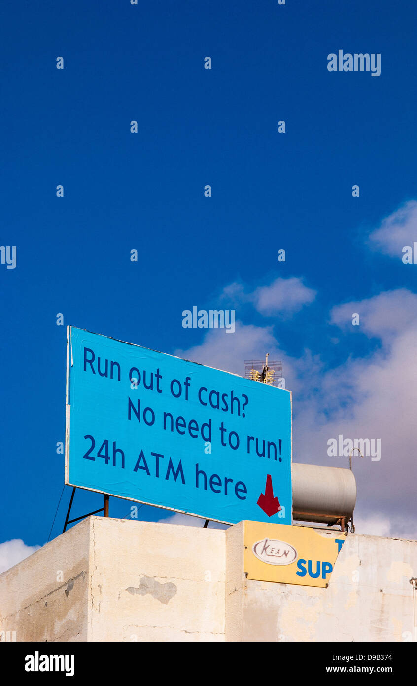 24 hour ATM sign on the roof of a white rendered building set against a ...