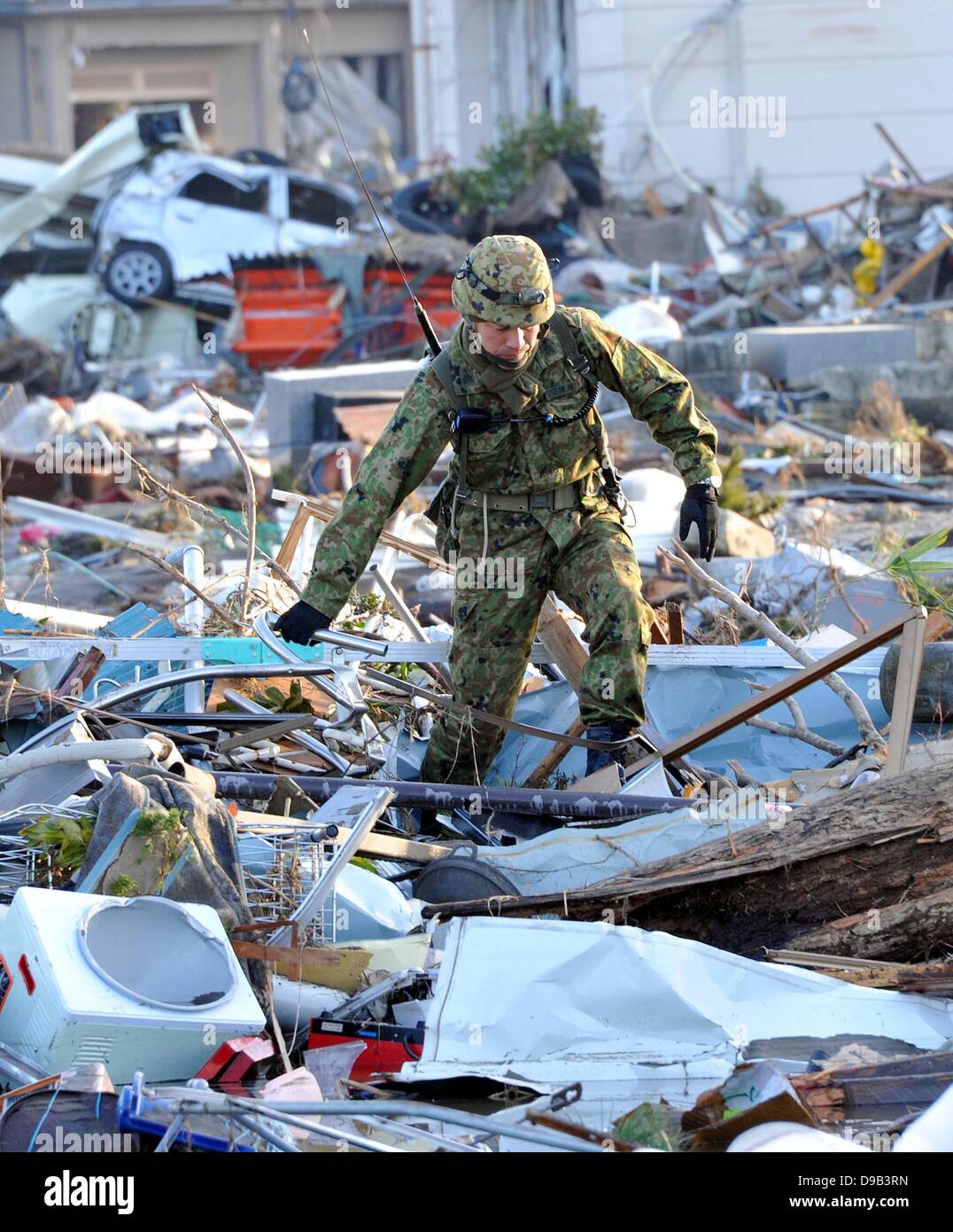 A Japan Ground Self-Defense Force trooper shifts through the debris as ...