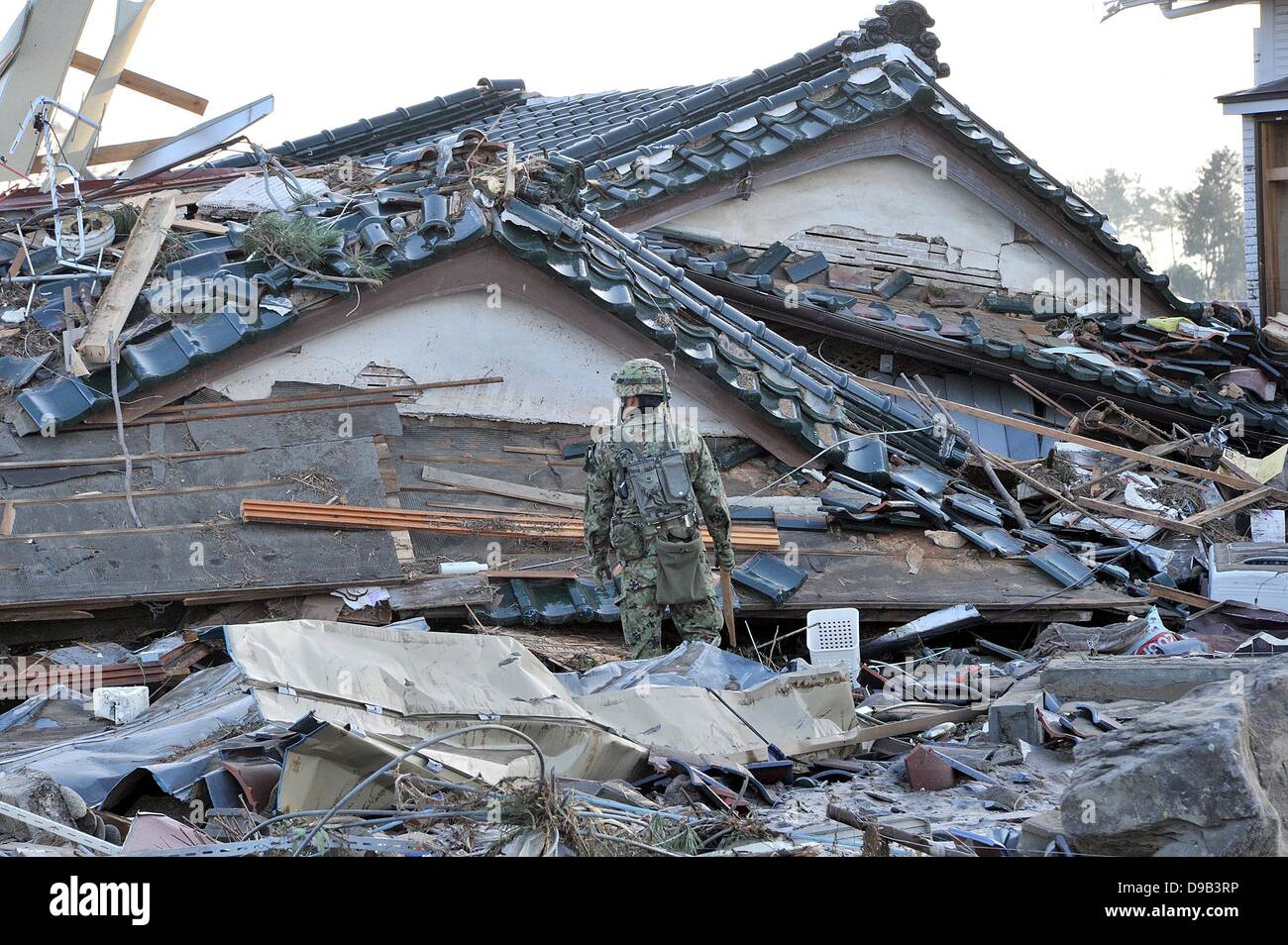 A Japan Ground Self-Defense Force trooper stands in front of collapsed ...