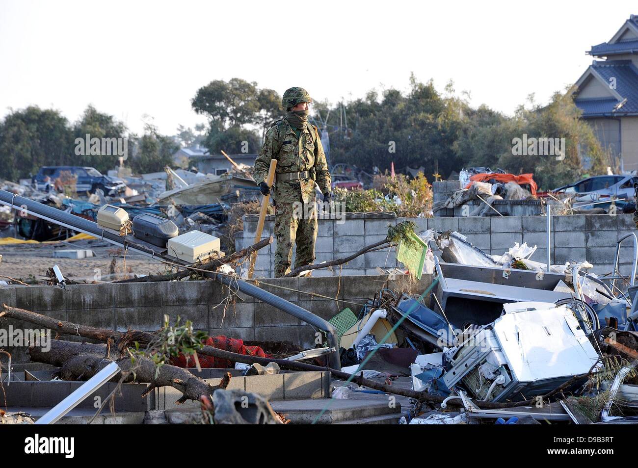 A Japan Ground Self-Defense Force trooper stands in the field of debris ...