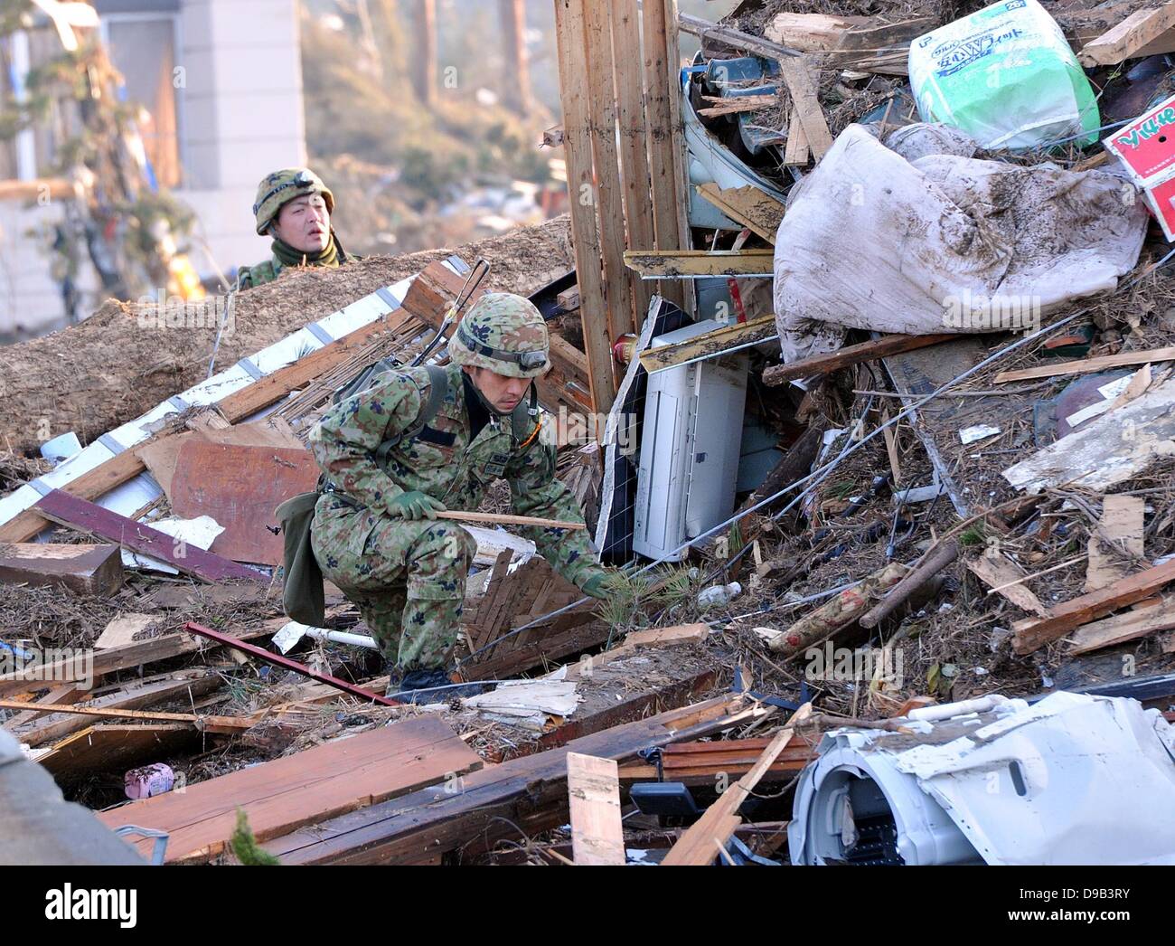 Japan Ground Self-Defense Force troopers shift through the debris as ...