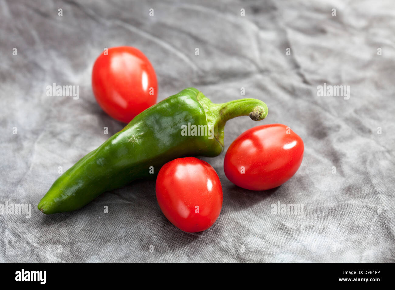 Green pepper and mini plum tomatoes on grey background, close up Stock ...