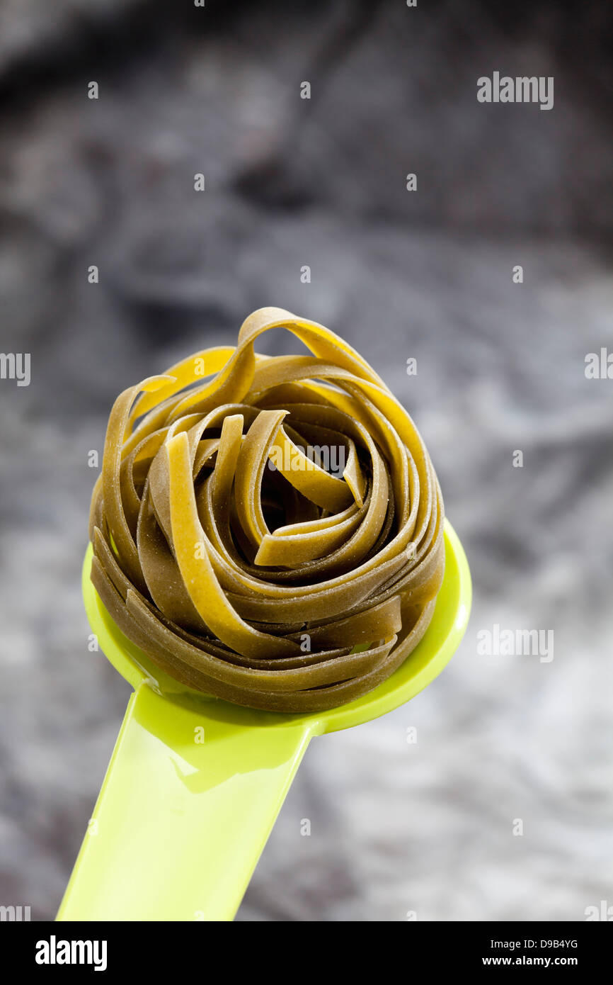Green noodles pasta on yellow plastic spoon, close up Stock Photo - Alamy